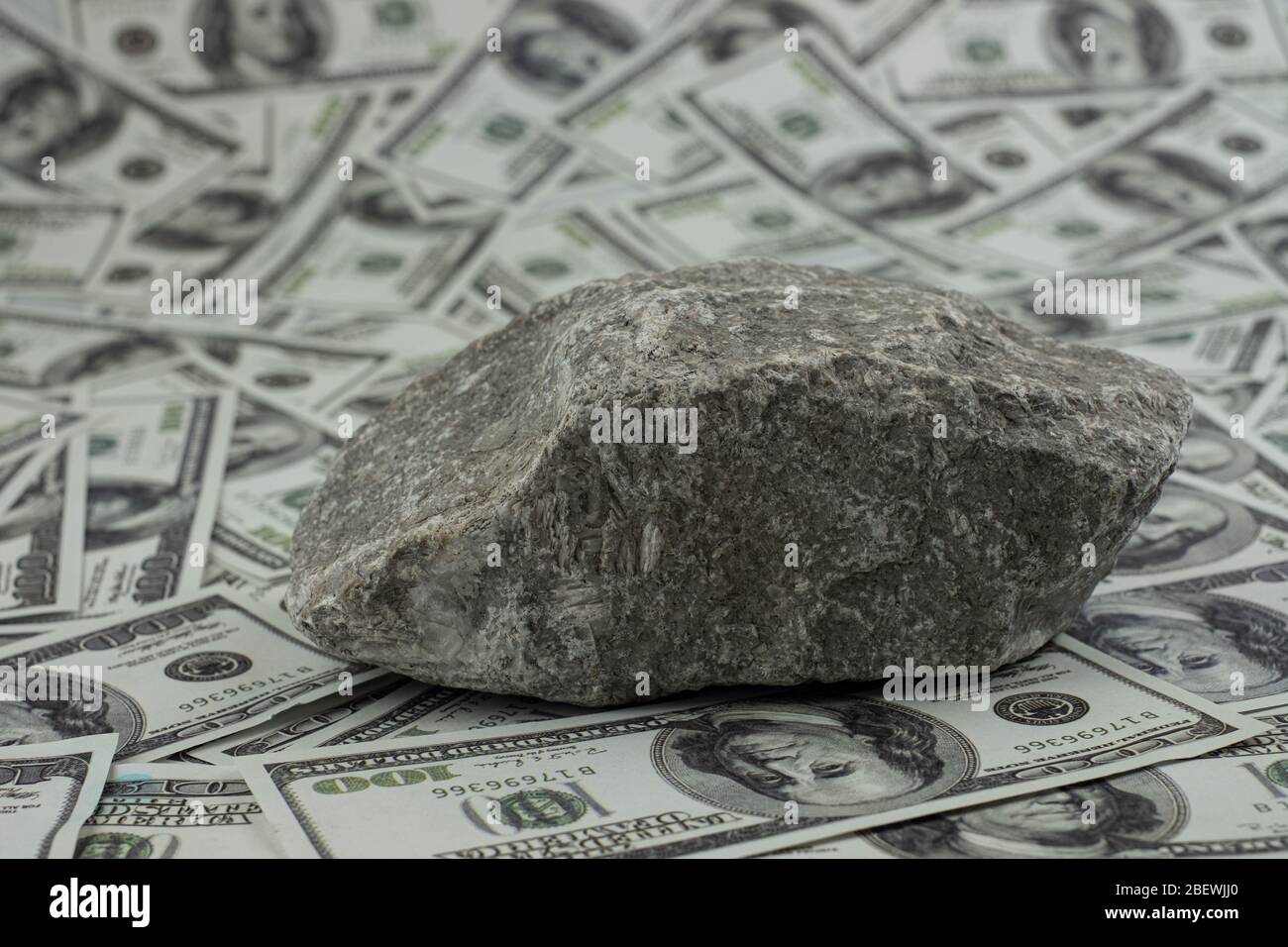 Stone on a group of money stack of 100 US dollars banknotes a lot of ...
