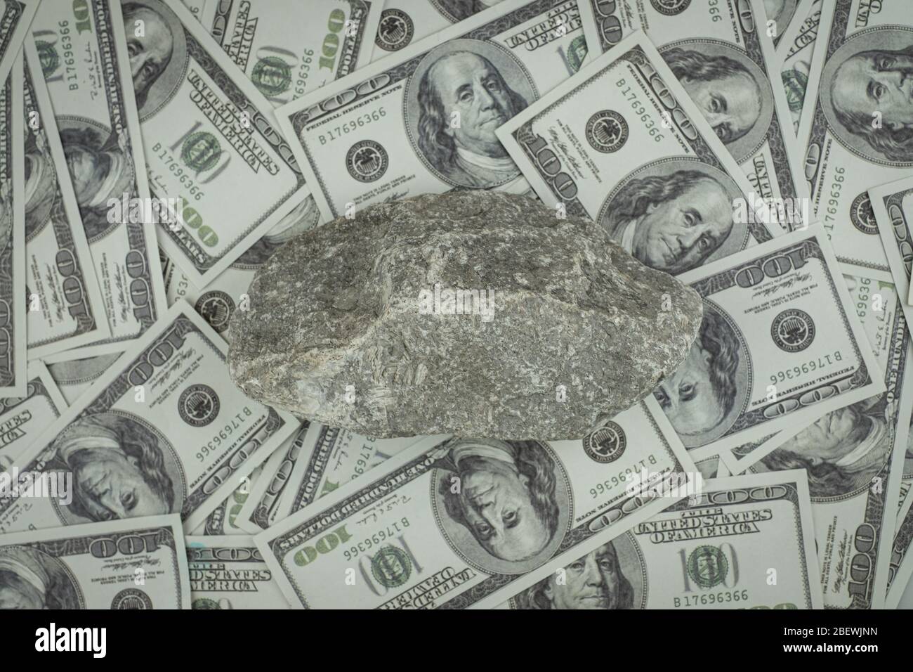 Stone on a group of money stack of 100 US dollars banknotes a lot of ...