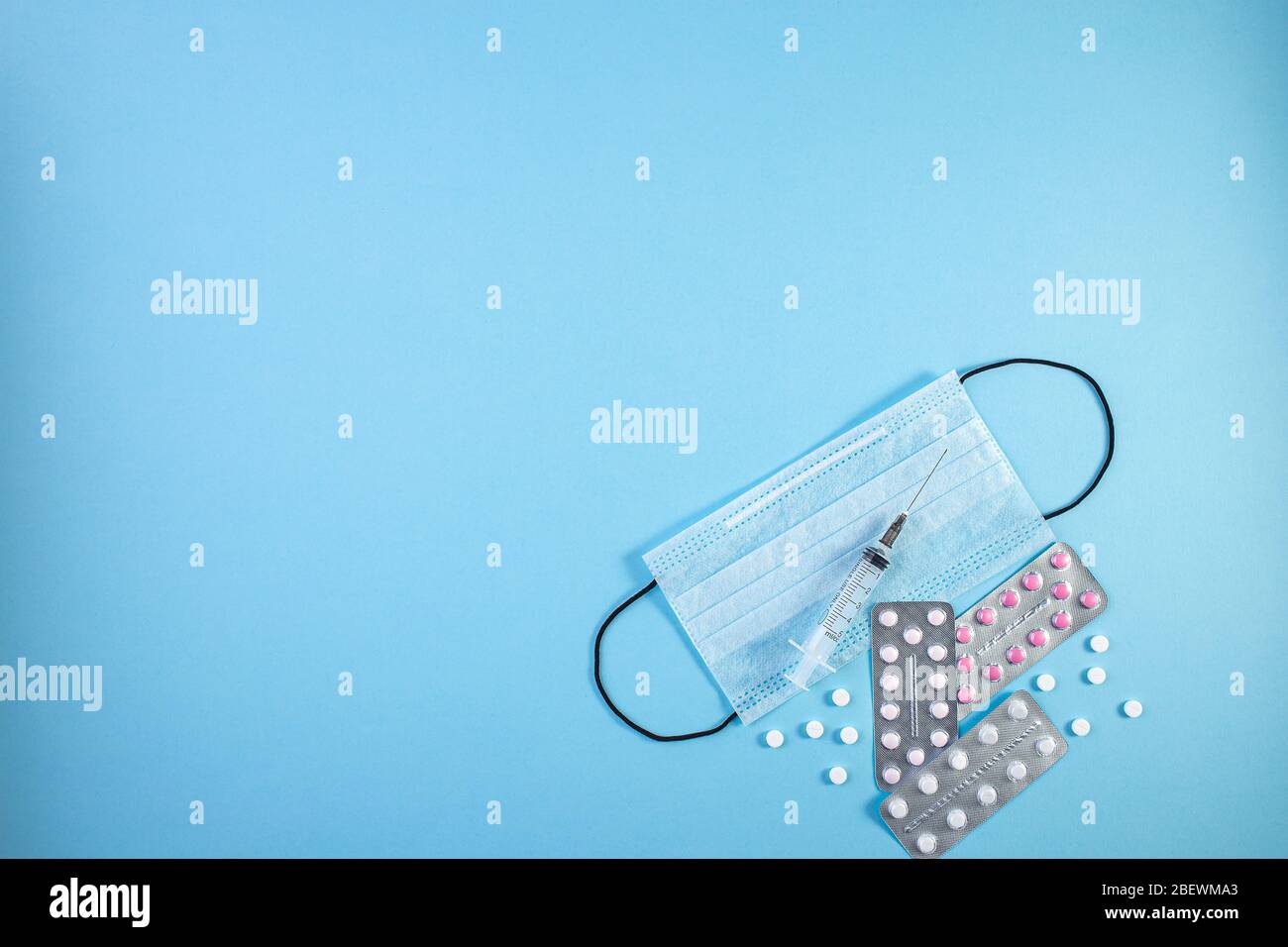 Protective medical mask, pills and syringe on blue background ...