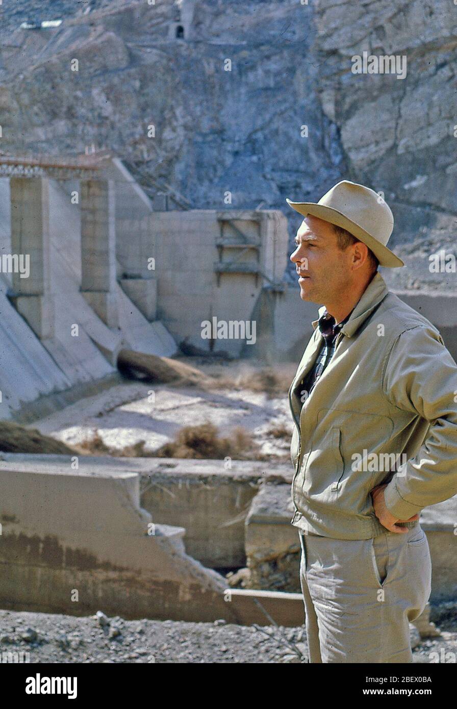 A man pictured with a dam and mountains in the background Stock Photo ...