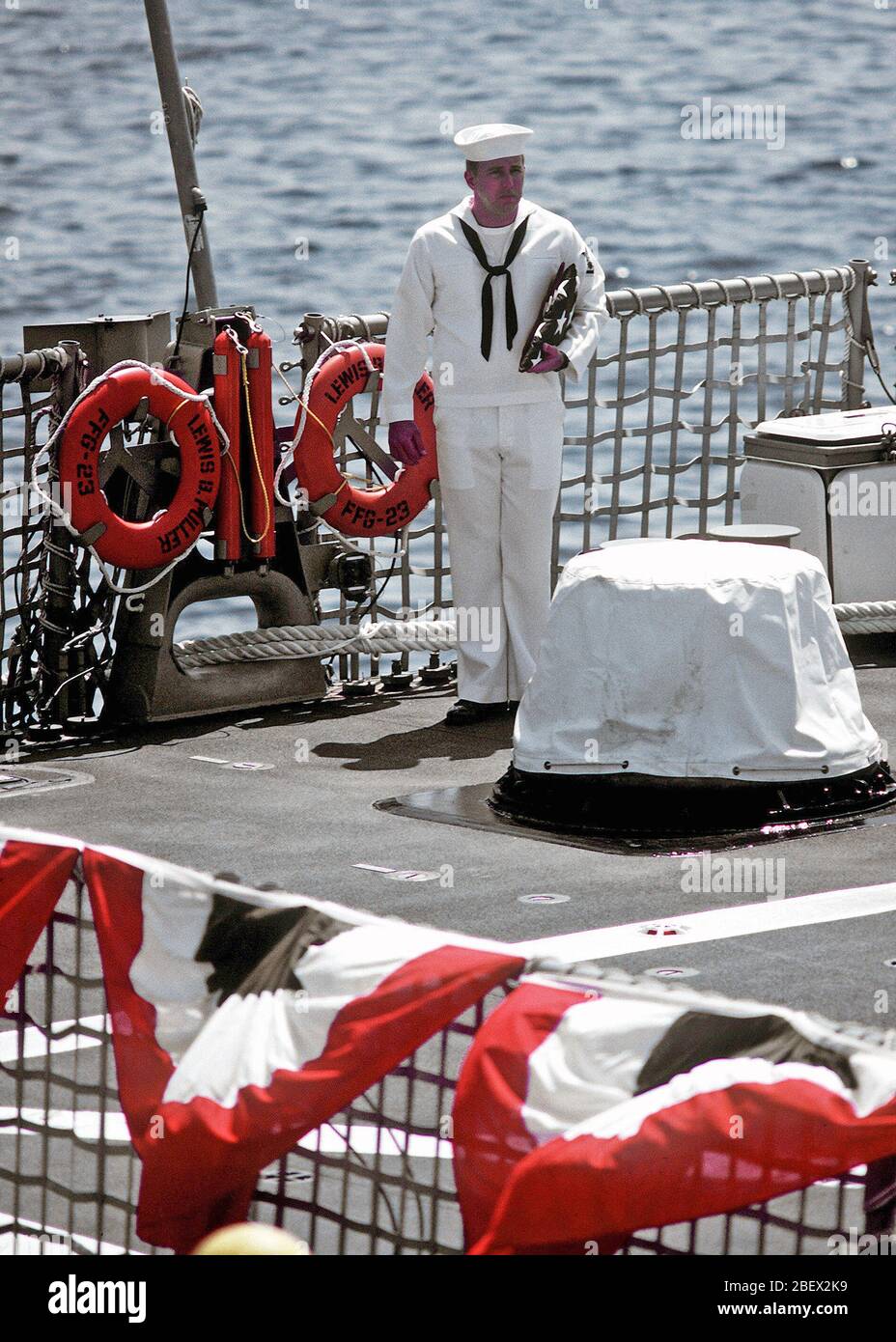 1982 - A crewman prepares to raise the flag during commissioning ...