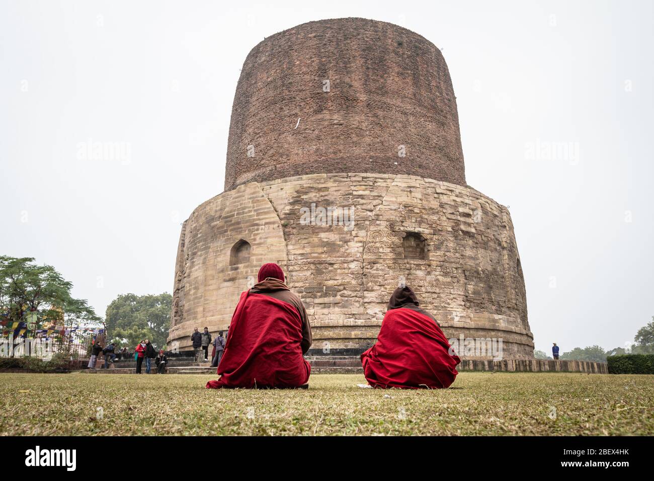 Two indian monks dressed in red robes sit on the grass before the big ...