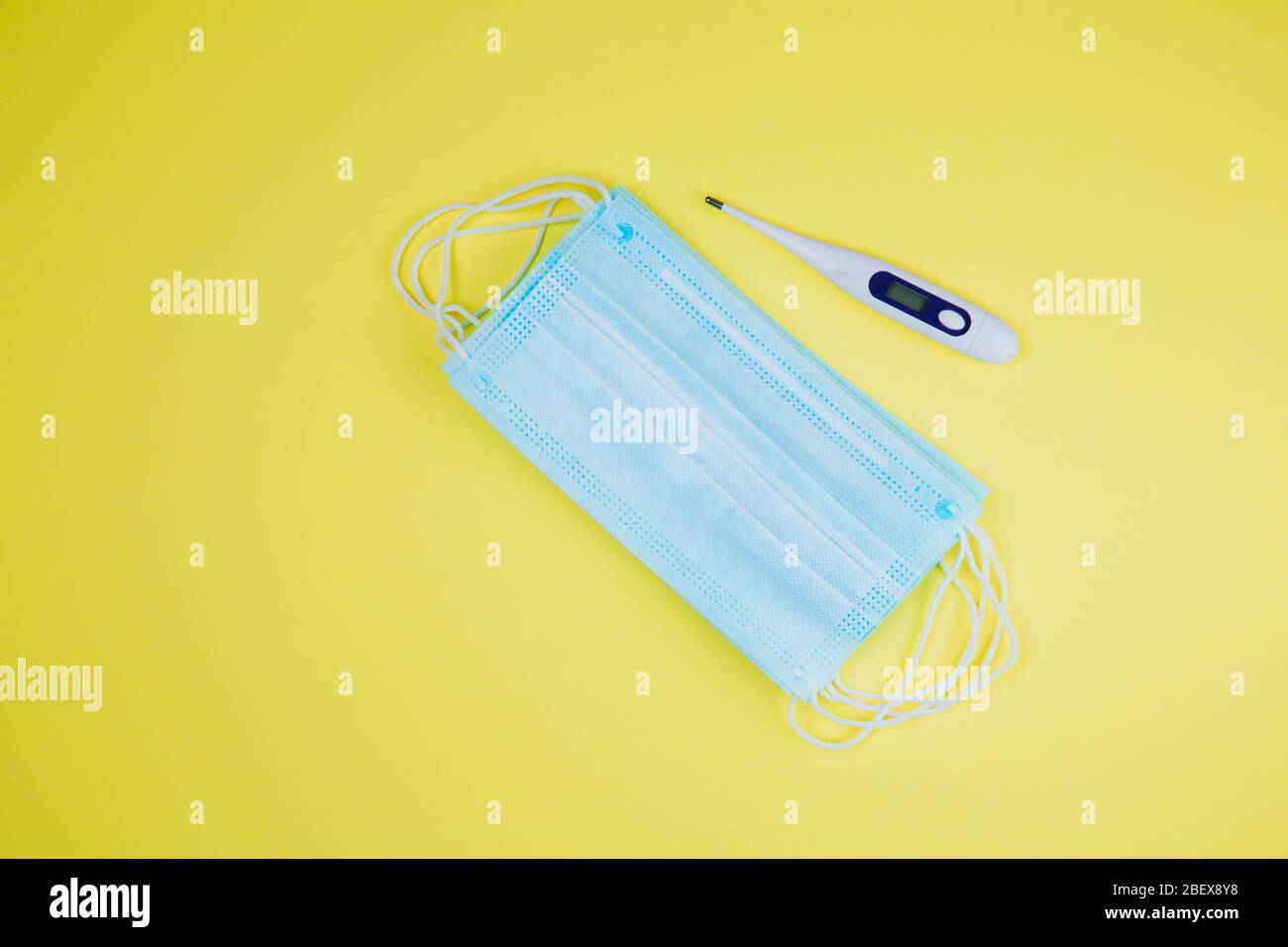 Medical masks and digital thermometer on a yellow background ...