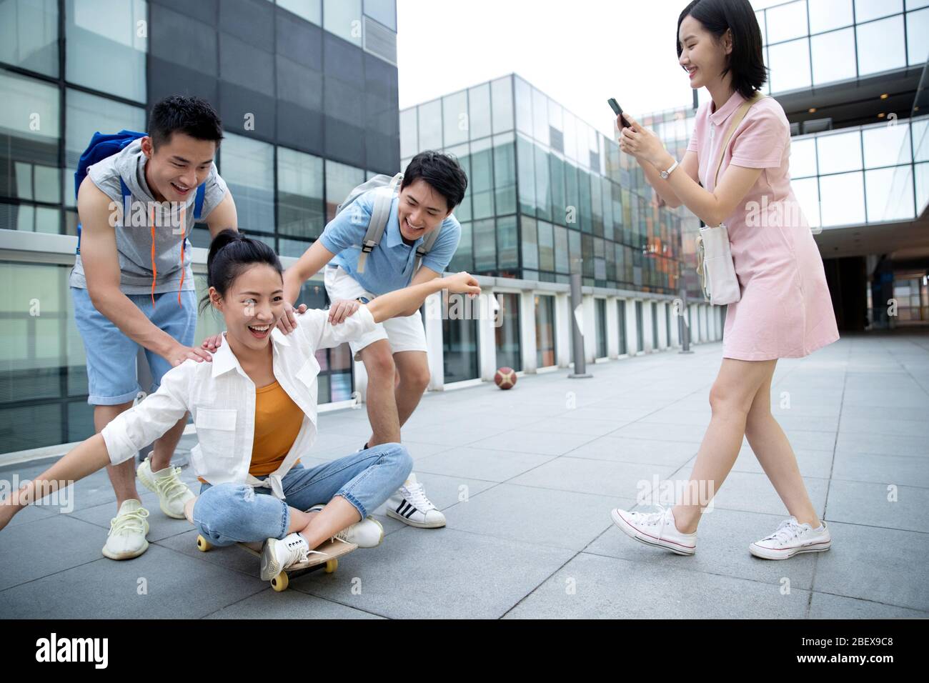 The young man pushes forward female classmate sat on a skateboard Stock ...