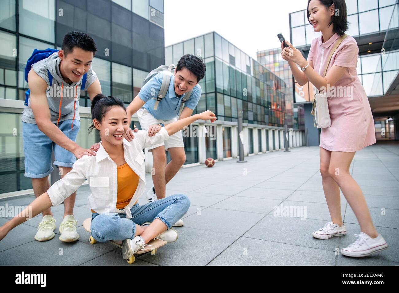 The young man pushes forward female classmate sat on a skateboard Stock ...