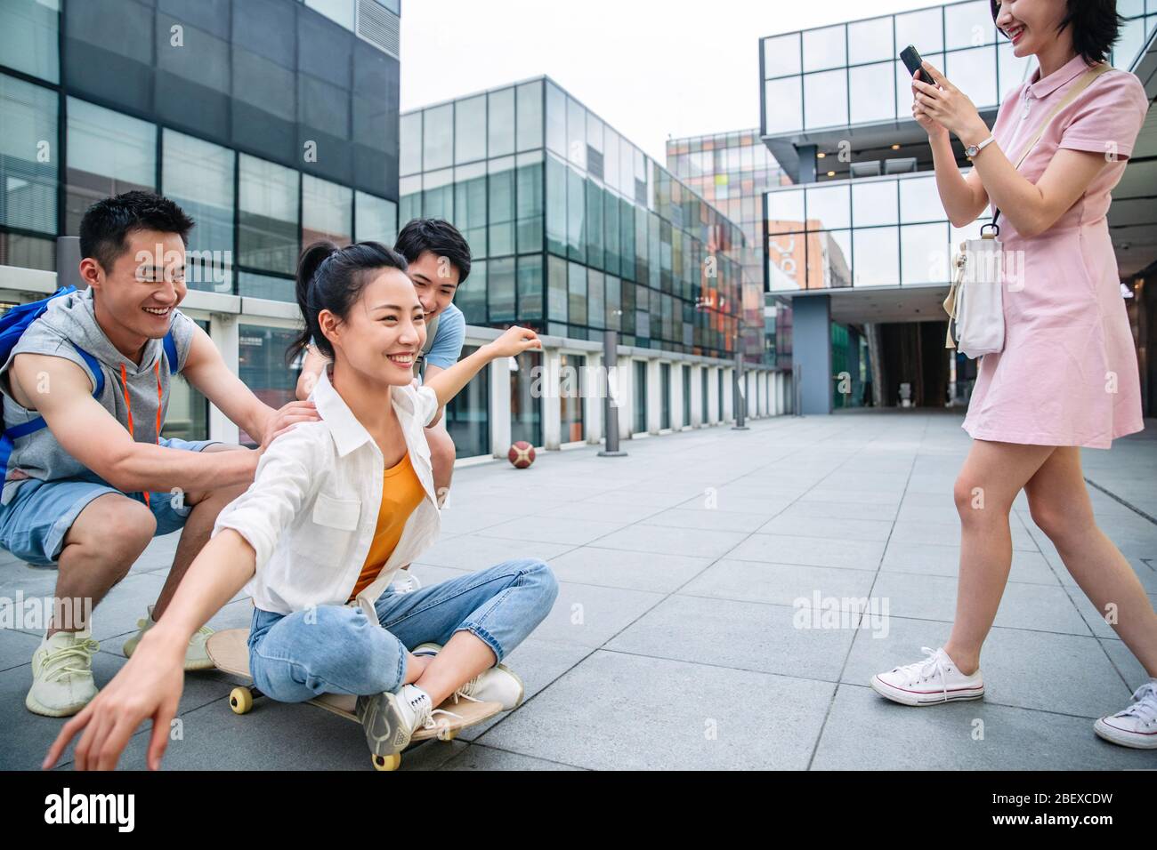 The young man pushes forward female classmate sat on a skateboard Stock ...