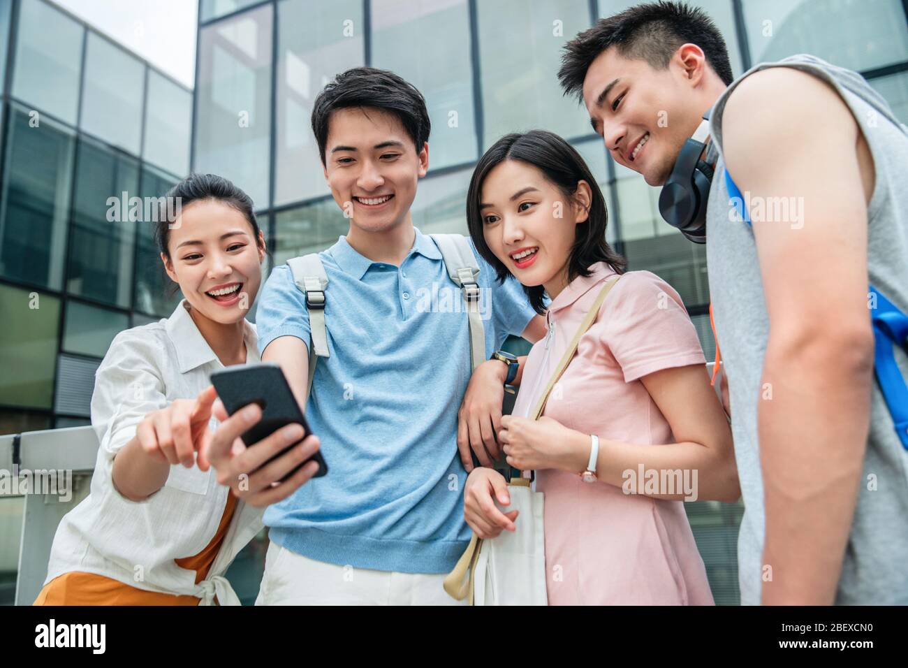 Outdoor four college students watch mobile phone Stock Photo - Alamy