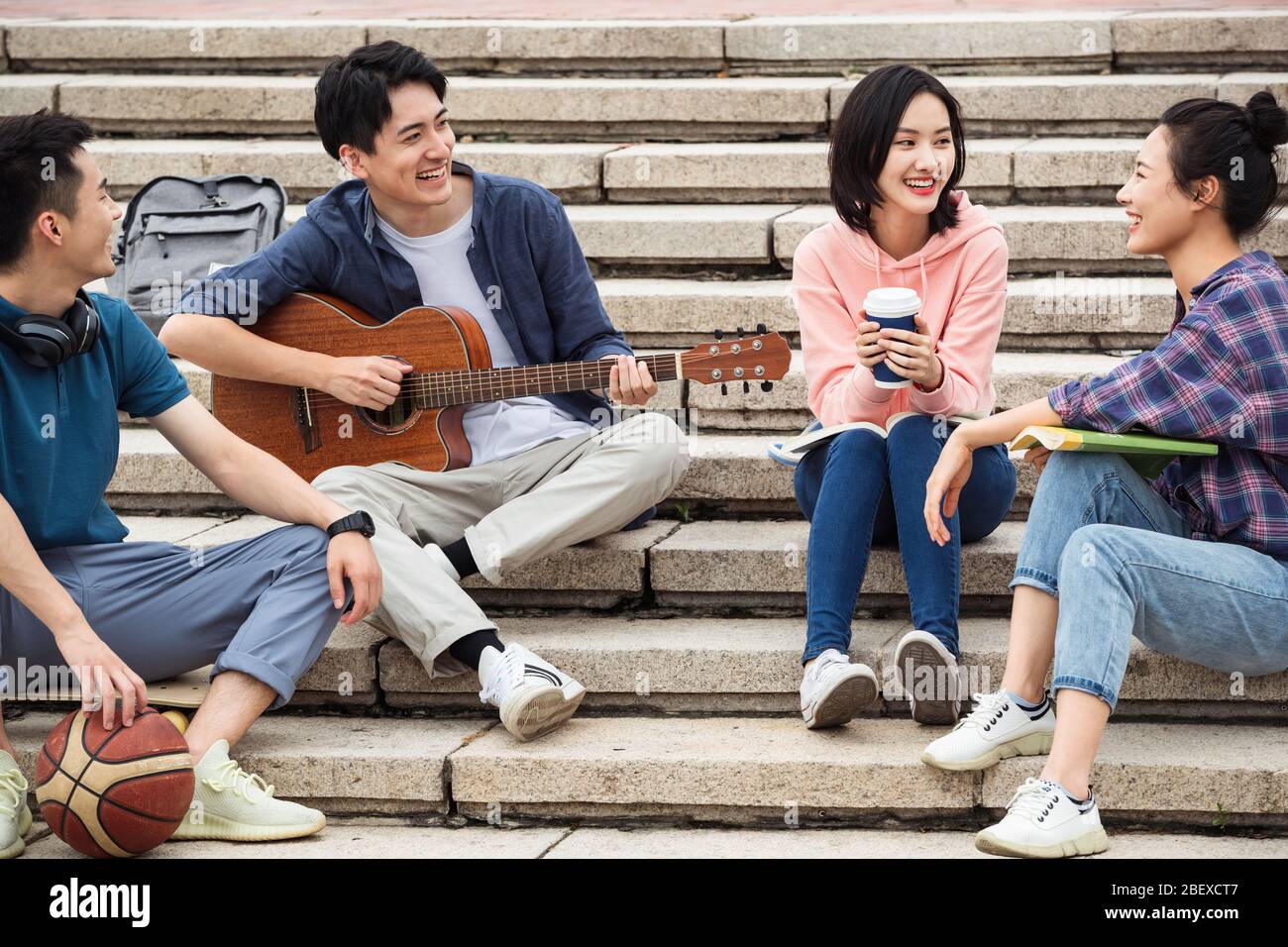 The young college students sat on the steps to play guitar Stock Photo ...