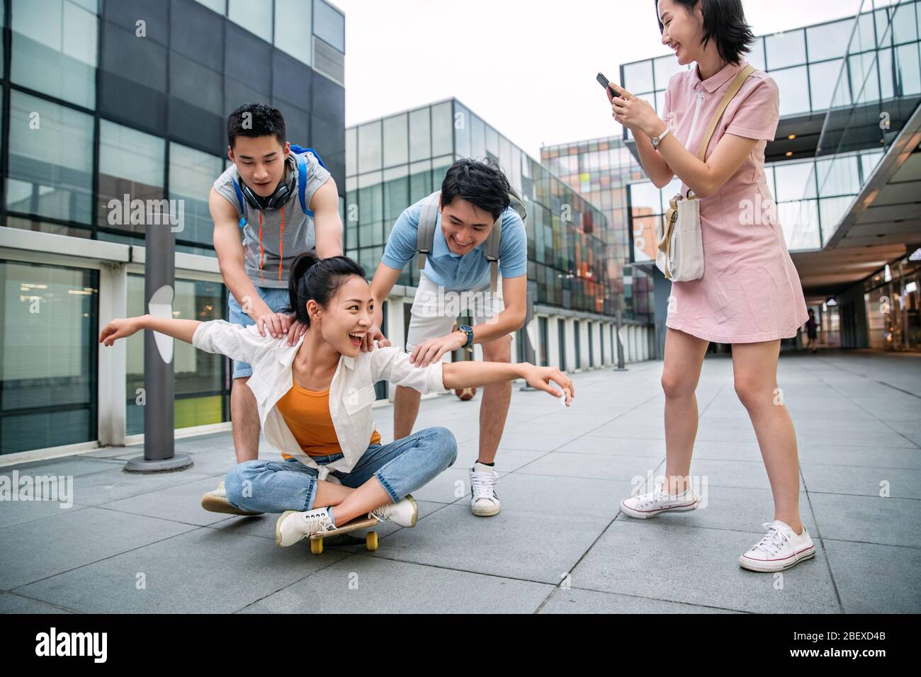 The young man pushes forward female classmate sat on a skateboard Stock ...