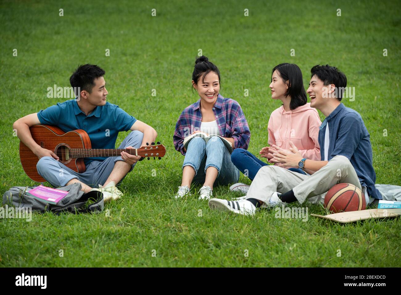 Happiness of college students play the guitar singing on the grass ...