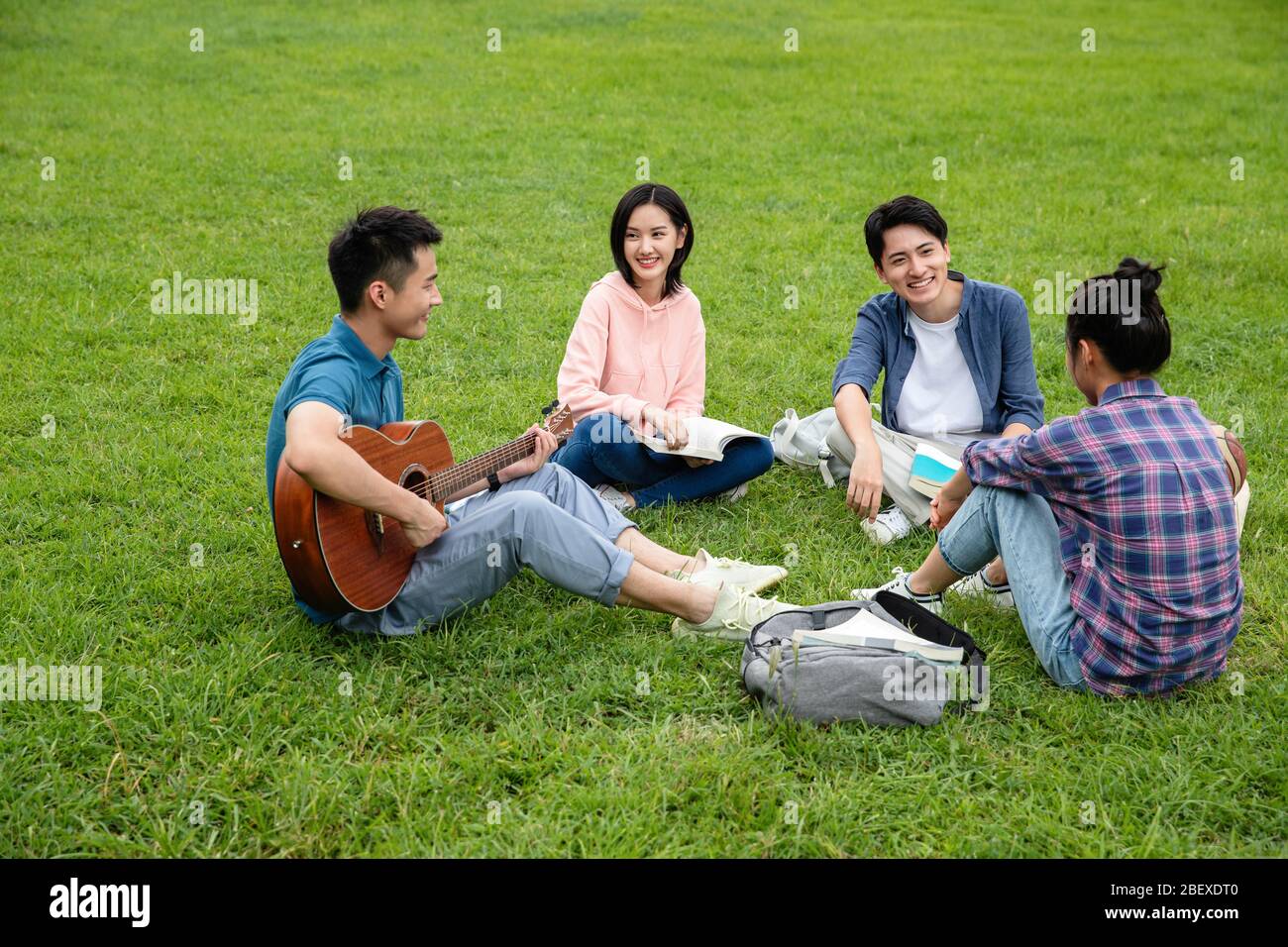 Happiness of college students play the guitar singing on the grass ...