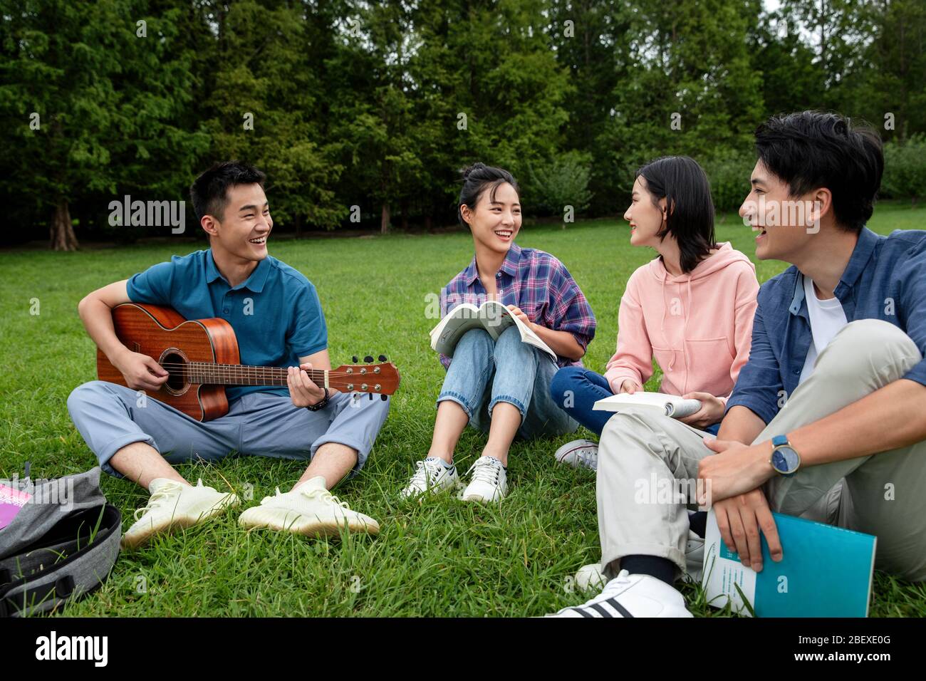 Happiness of college students play the guitar singing on the grass ...