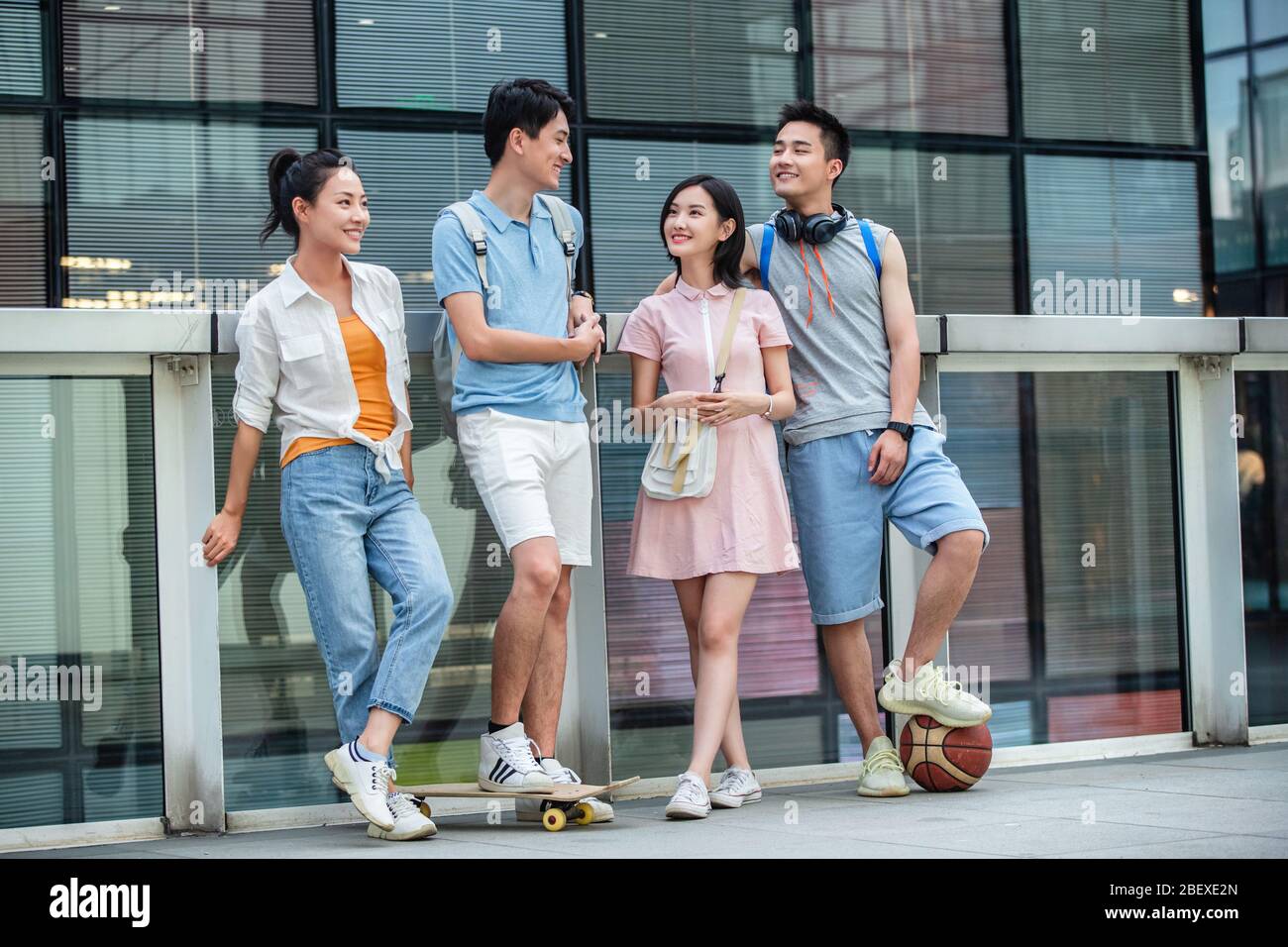 Outdoor happy college students lean on column while standing Stock ...