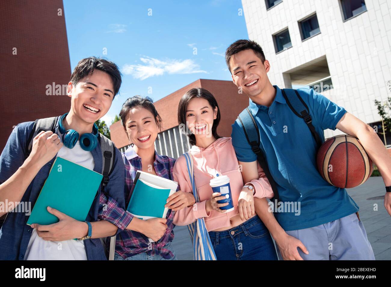 Four happy on the campus of college students holding together Stock ...