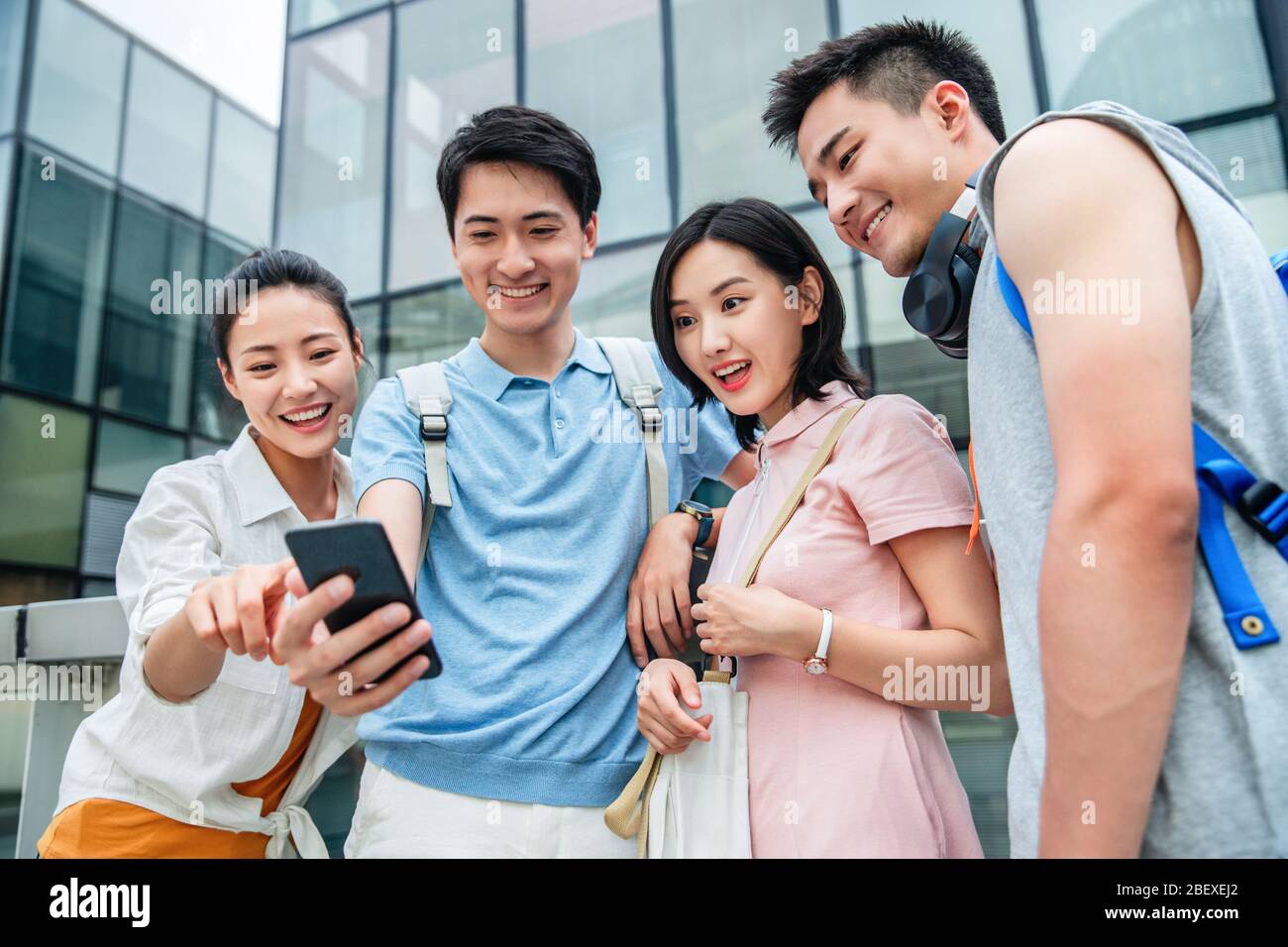 Outdoor four college students watch mobile phone Stock Photo - Alamy