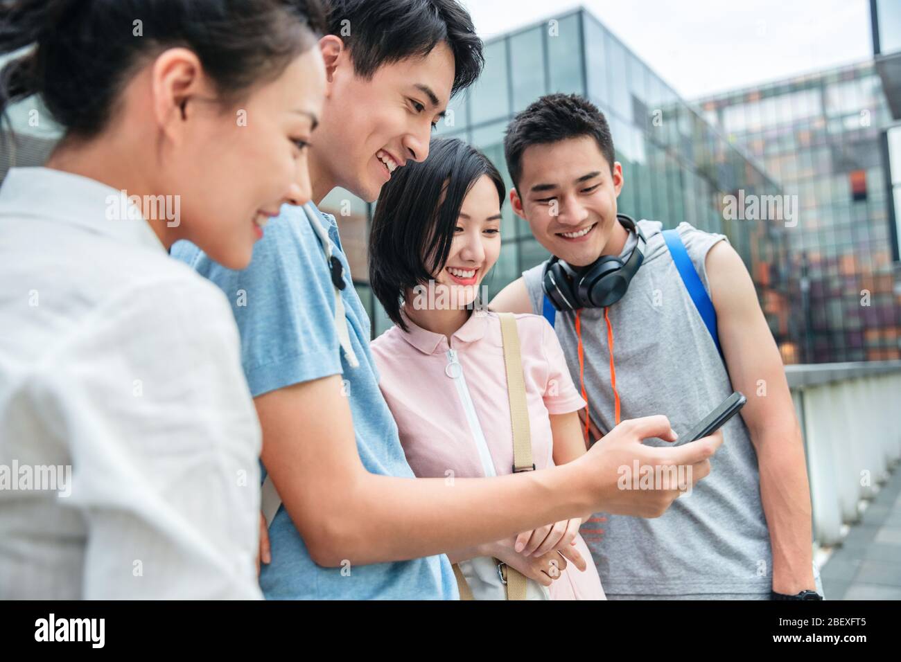 Outdoor four college students watch mobile phone Stock Photo - Alamy