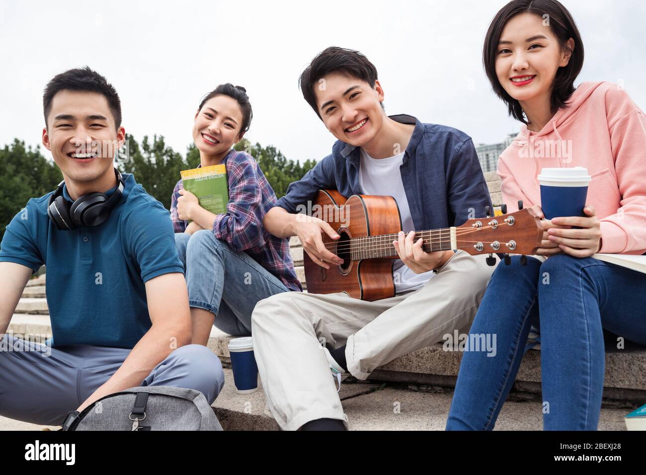 The young college students sat on the steps to play guitar Stock Photo ...