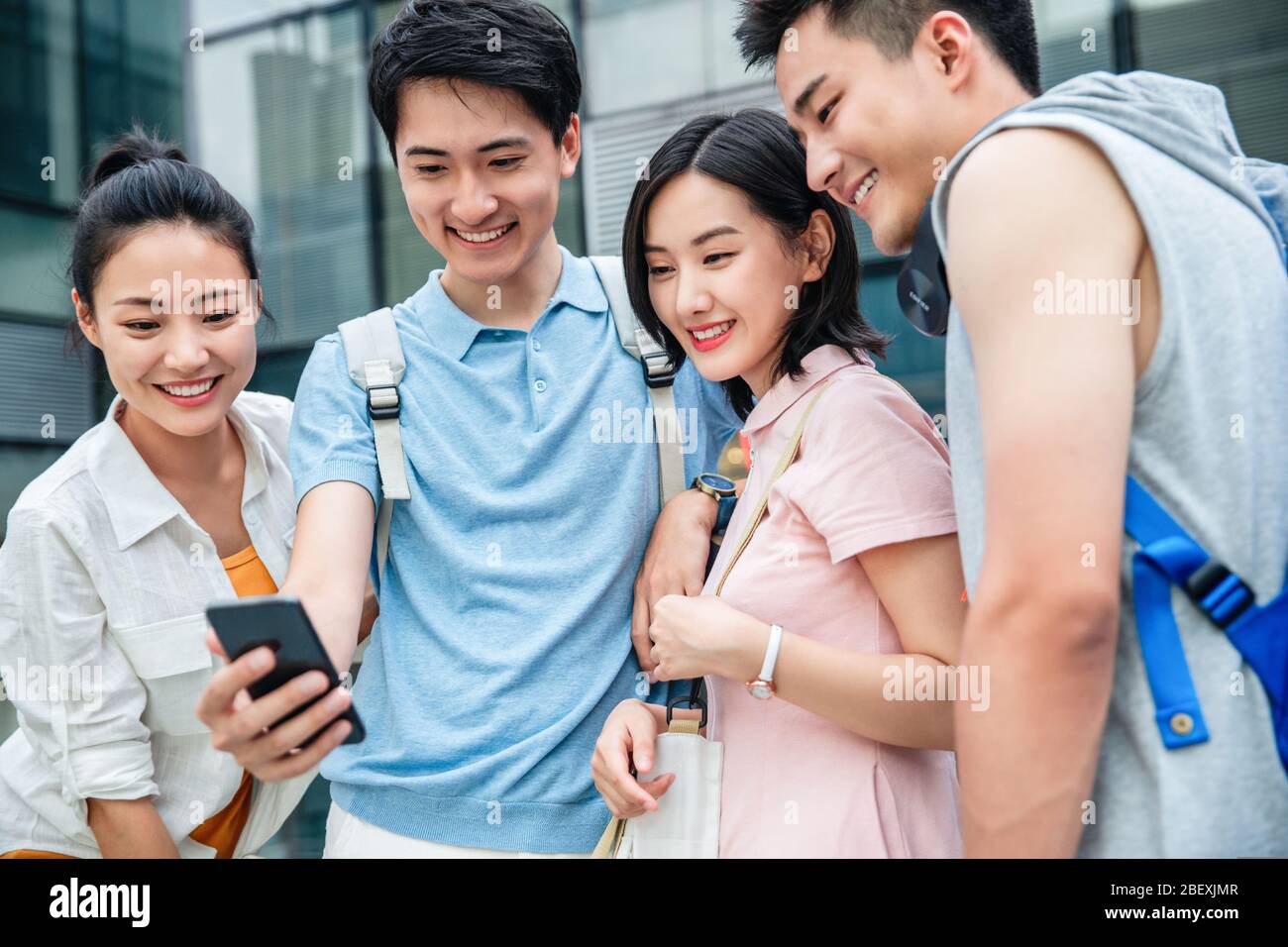 Outdoor four college students watch mobile phone Stock Photo - Alamy