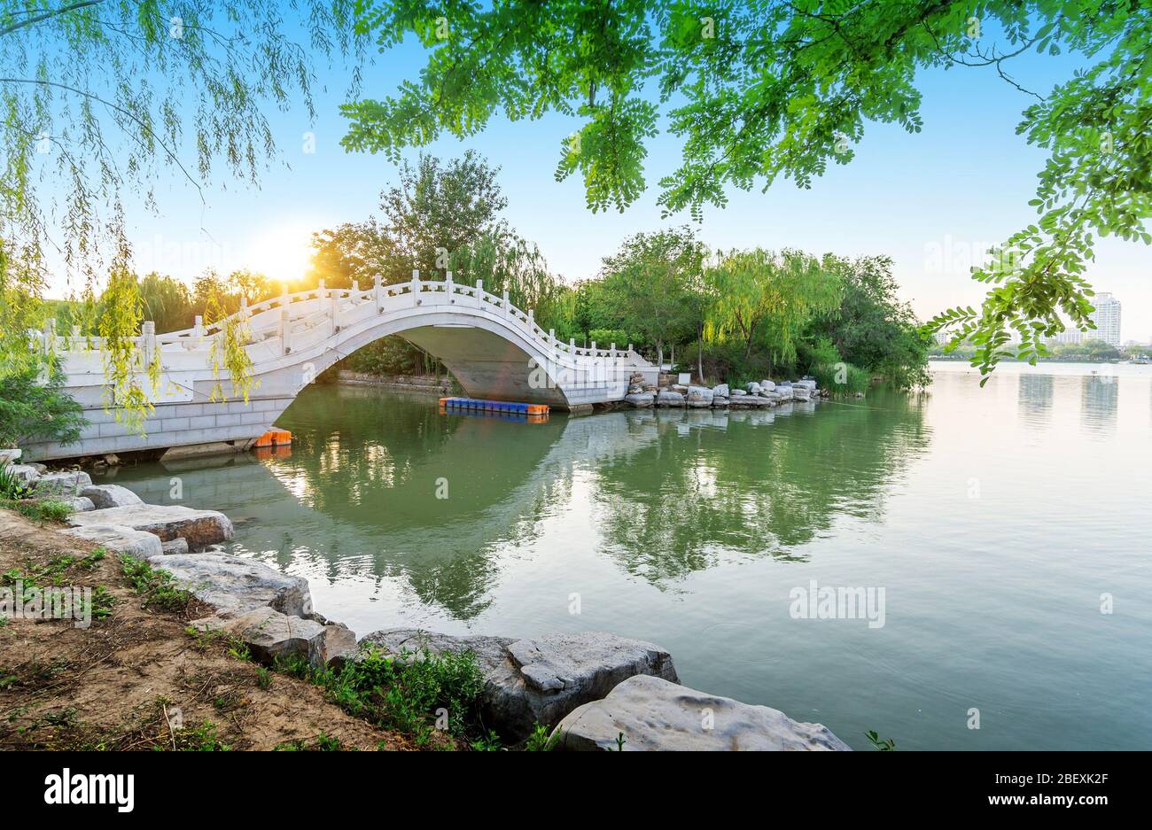 Old style stone Chinese arch bridge in a green garden pond in Beijing ...