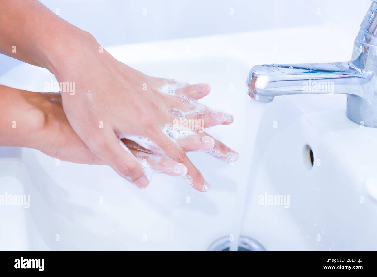 young women washing hands with soap rubbing fingers and skin under ...