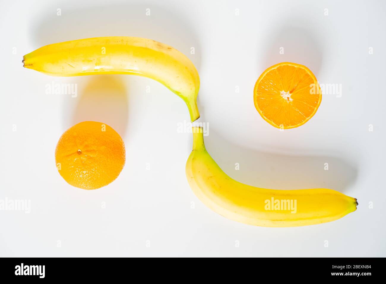 Two whole bananas laid at opposite ends with two orange halves to ...