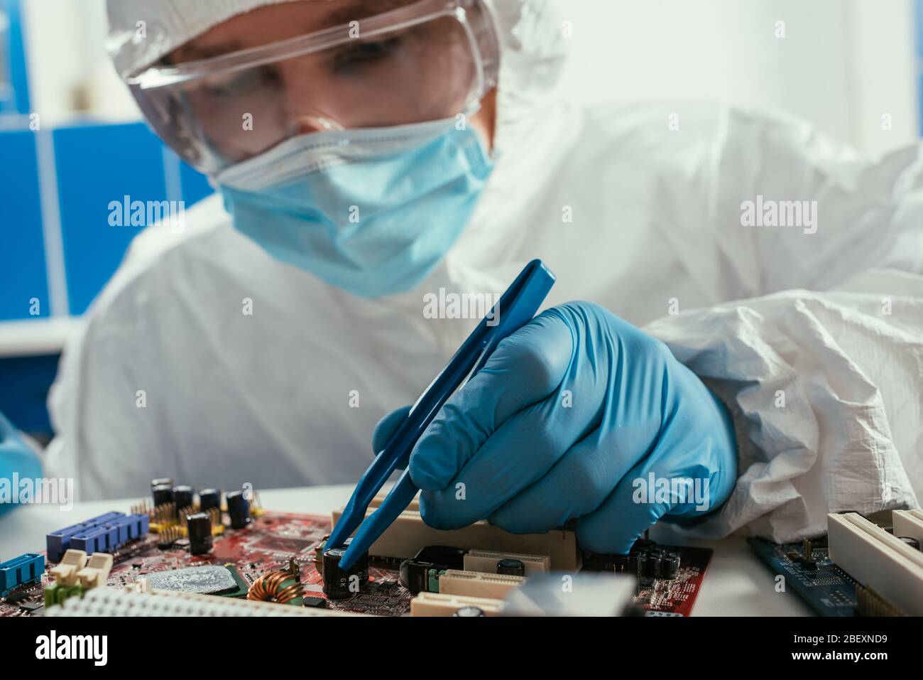 engineer in medical mask and goggles fixing computer motherboard with ...