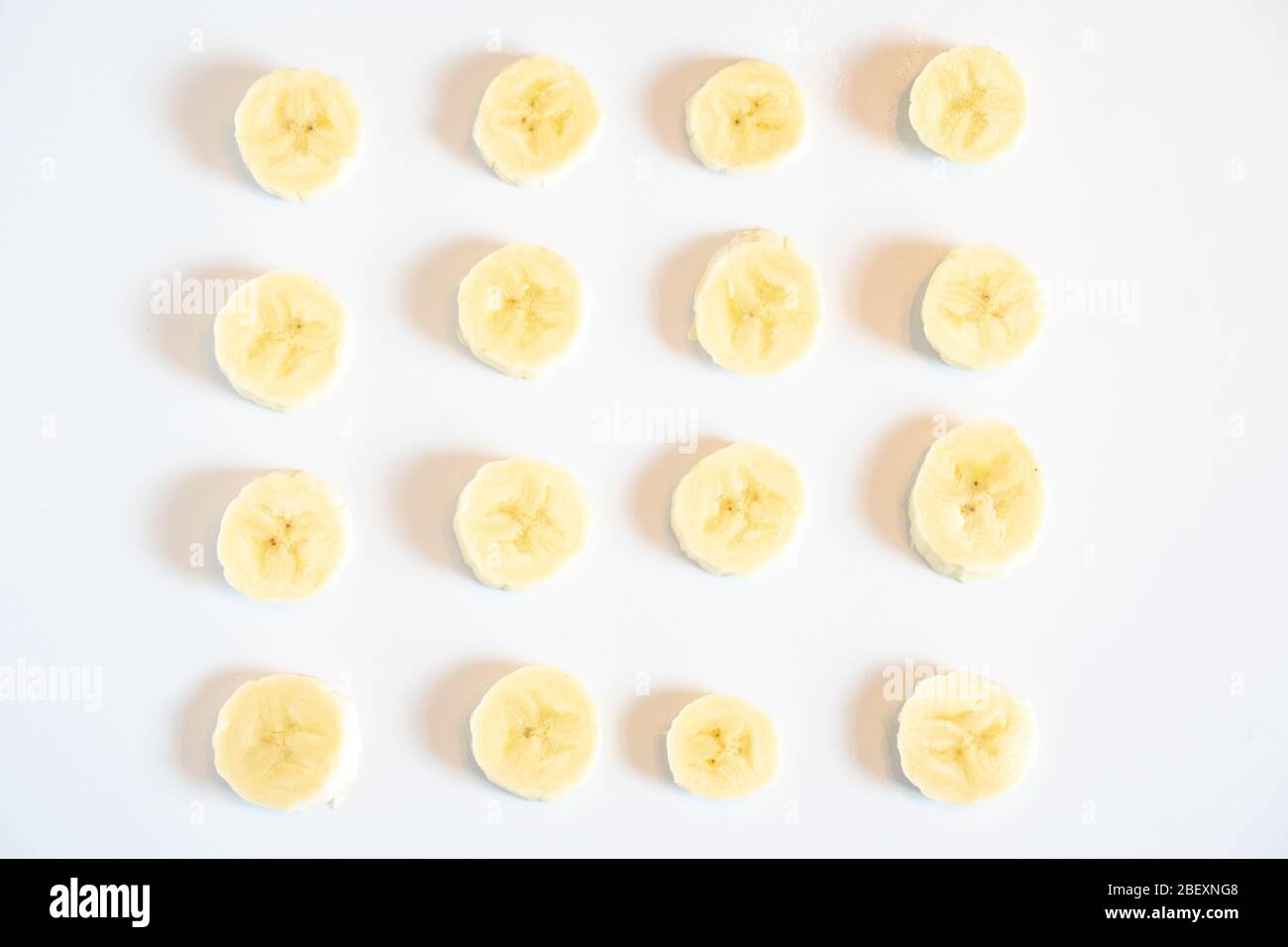 An array of sliced banana pieces laid out in a square pattern against a ...