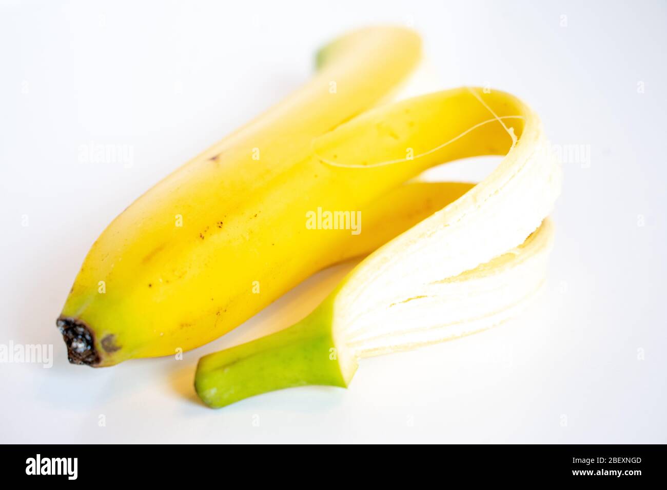 A banana peeled back to reveal the inside against a plain white ...