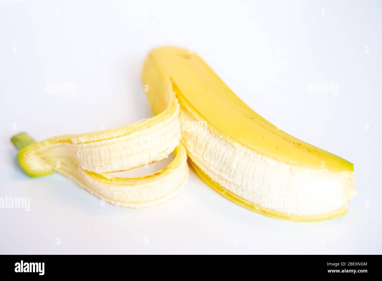 A banana peeled back to reveal the inside against a plain white ...