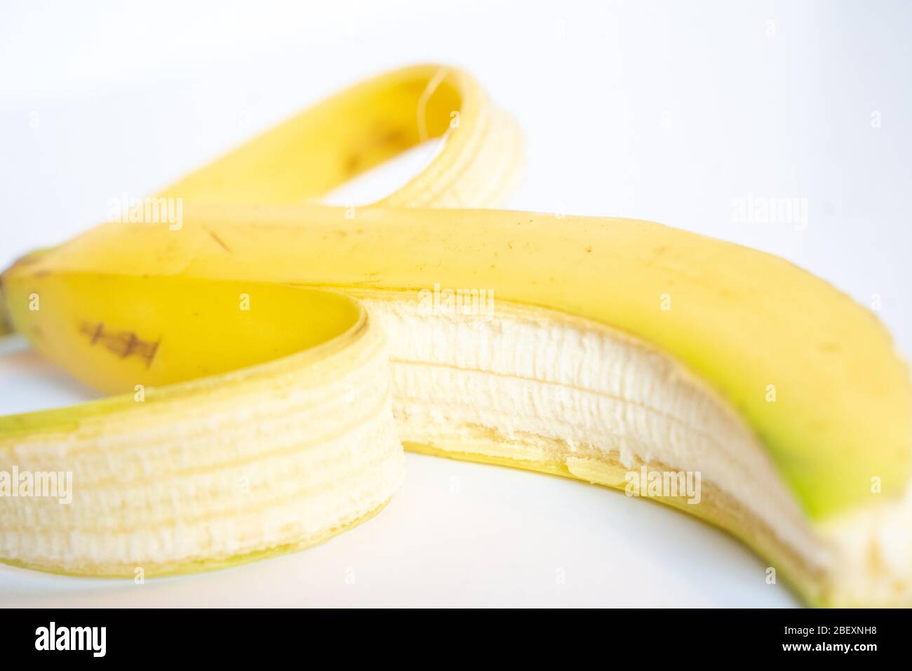 A banana peeled back to reveal the inside against a plain white ...