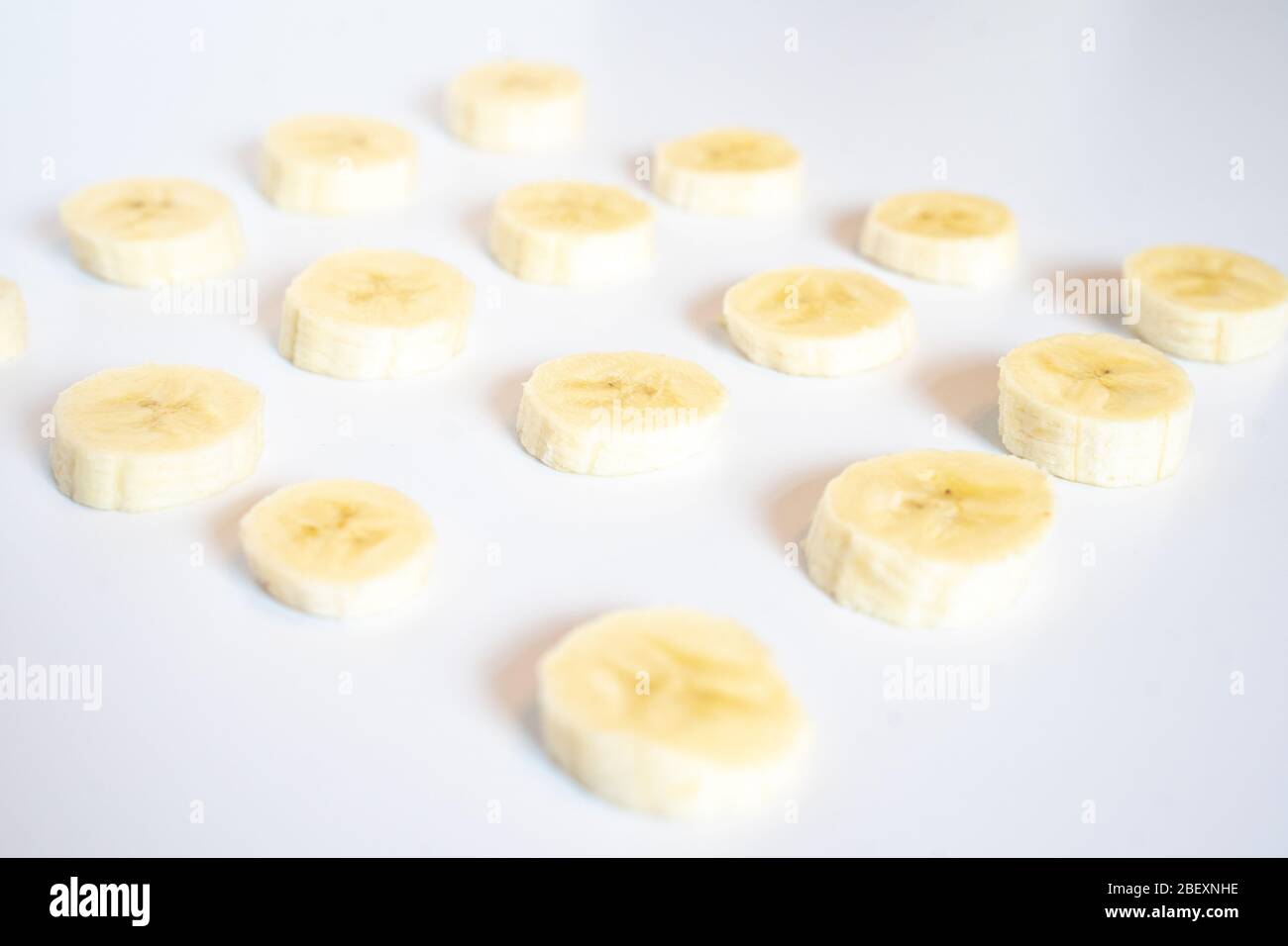 An array of sliced banana pieces laid out in a square pattern against a ...