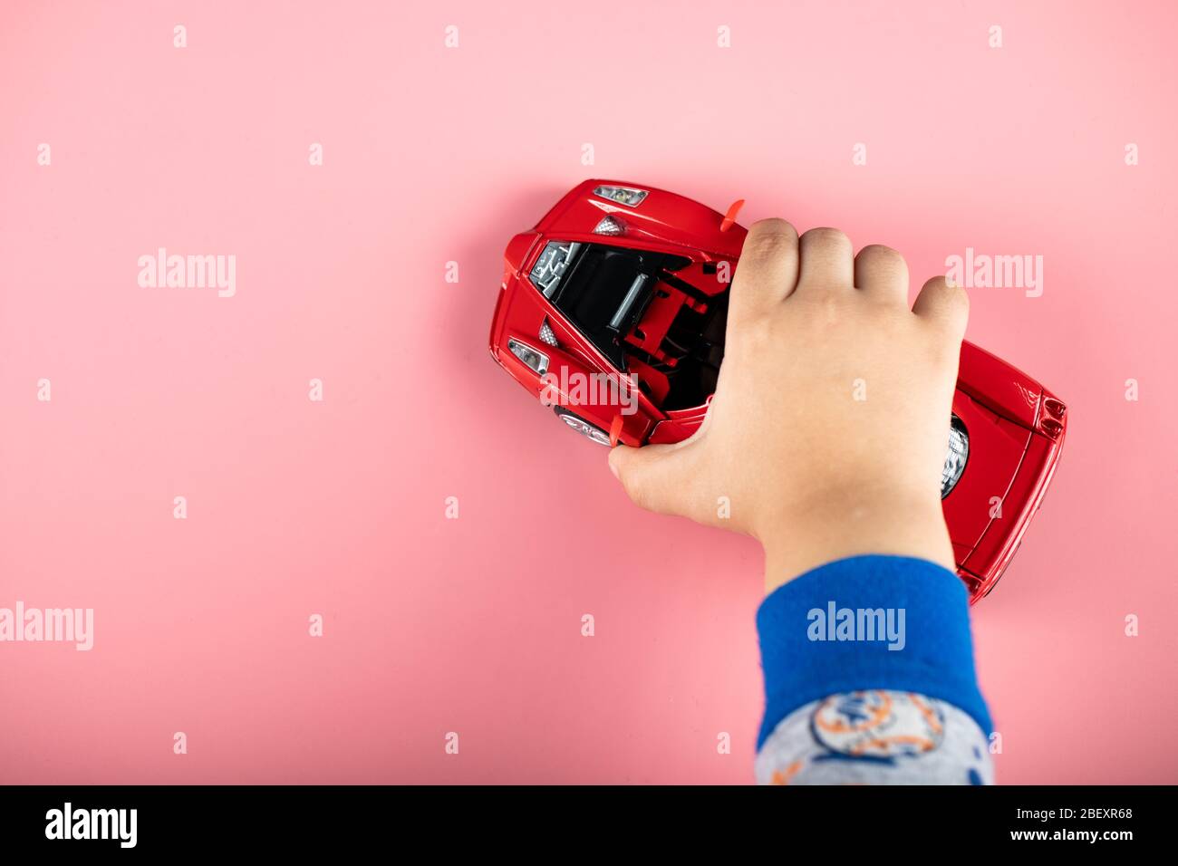 Small red car toy for a kid,a child playing with it Stock Photo - Alamy