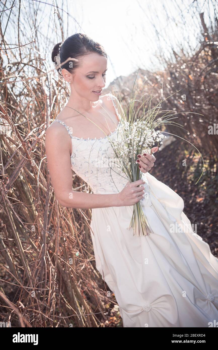 outdoor portrait of a bride with bridal bouquet in a wedding dress ...