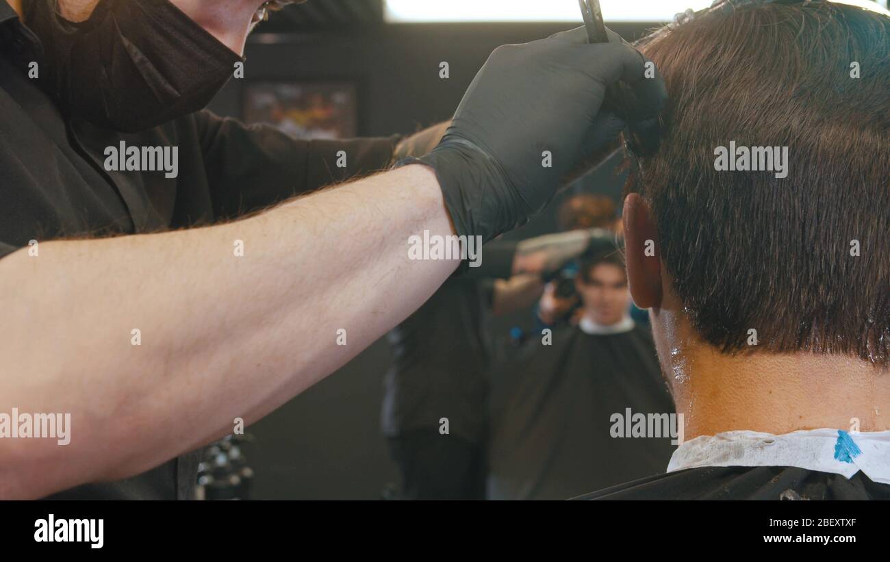 Barber cutting his client's hair in the barbershop. Mid shot Stock ...