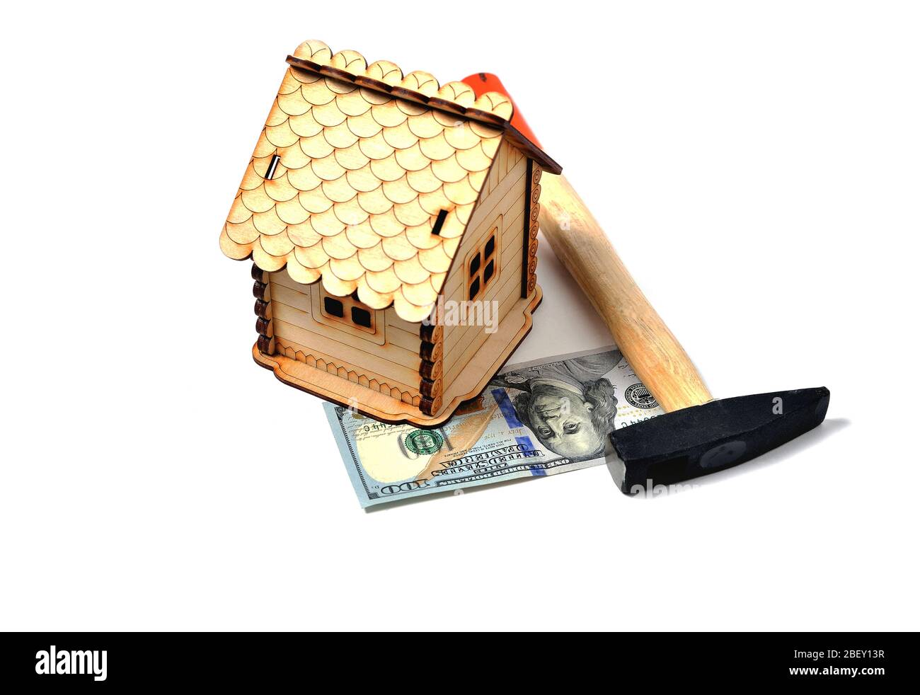 Wooden toy house, a banknote of 100 dollars and a hammer on a white ...