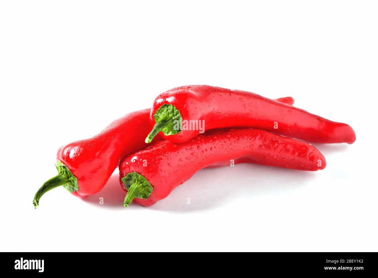 three red peppers of an elongated shape on a white background with ...