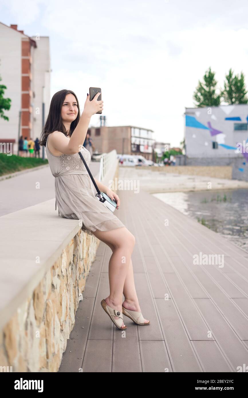 Girl with phone on pier. Pretty girl taking selfies in the city Stock ...