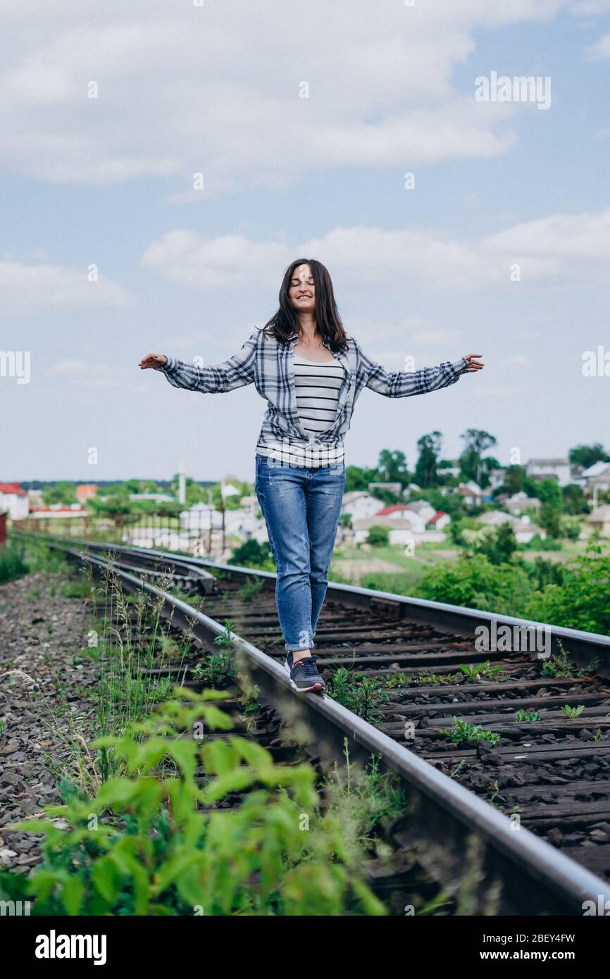 Happy girl at train station in summer sunny day. Brunette girl in jeans ...