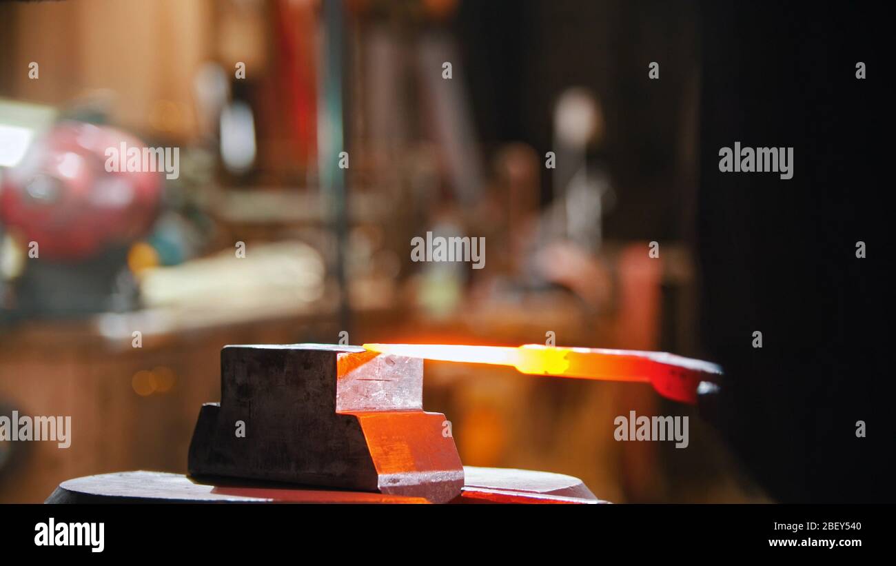 Forging an object out of hot metal using a pressure machine. Mid shot ...