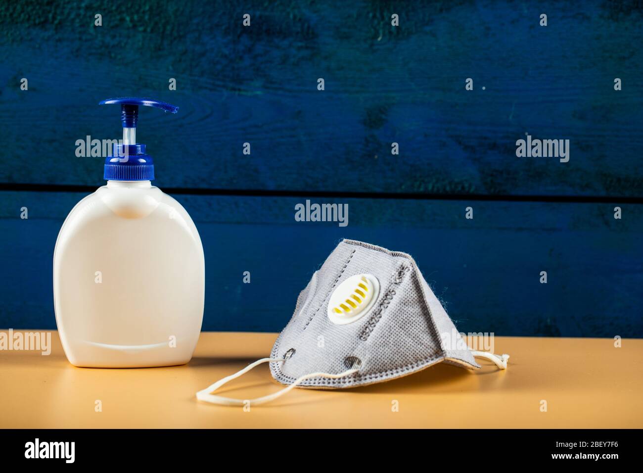 Blue modern face mask with a white sanitizer container isolated on ...