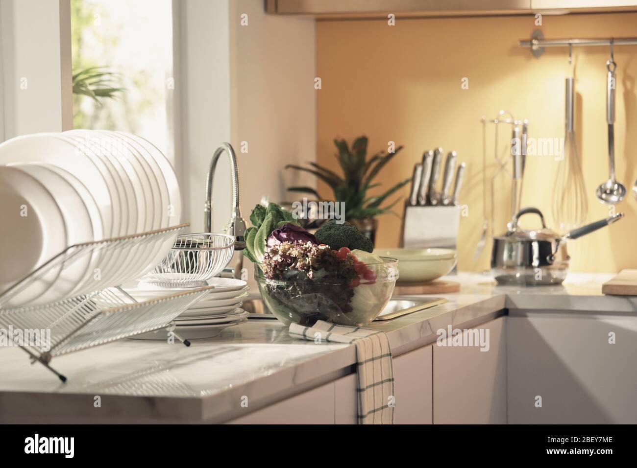 the big dish stack and a glass bowl of vegetable put on the sink ...