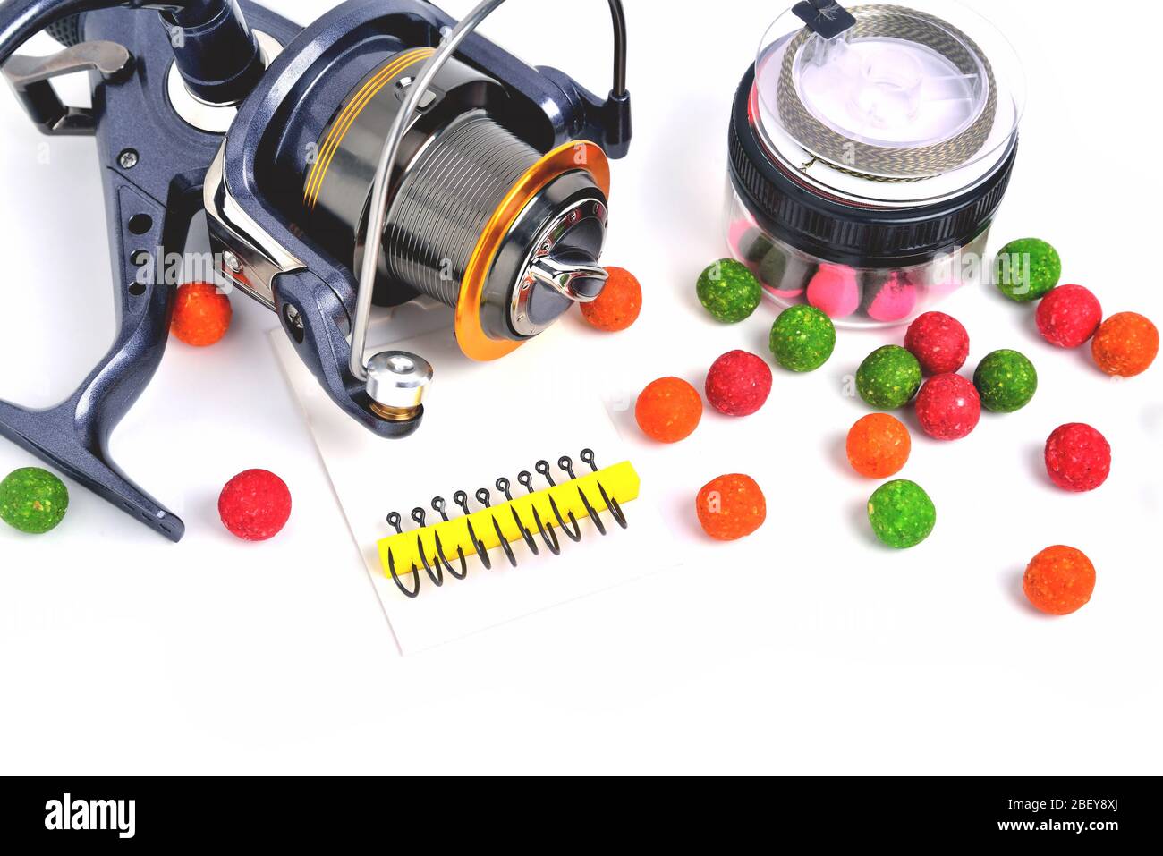 Fishing coil, carp hooks colored boilies, braided cord, on white ...