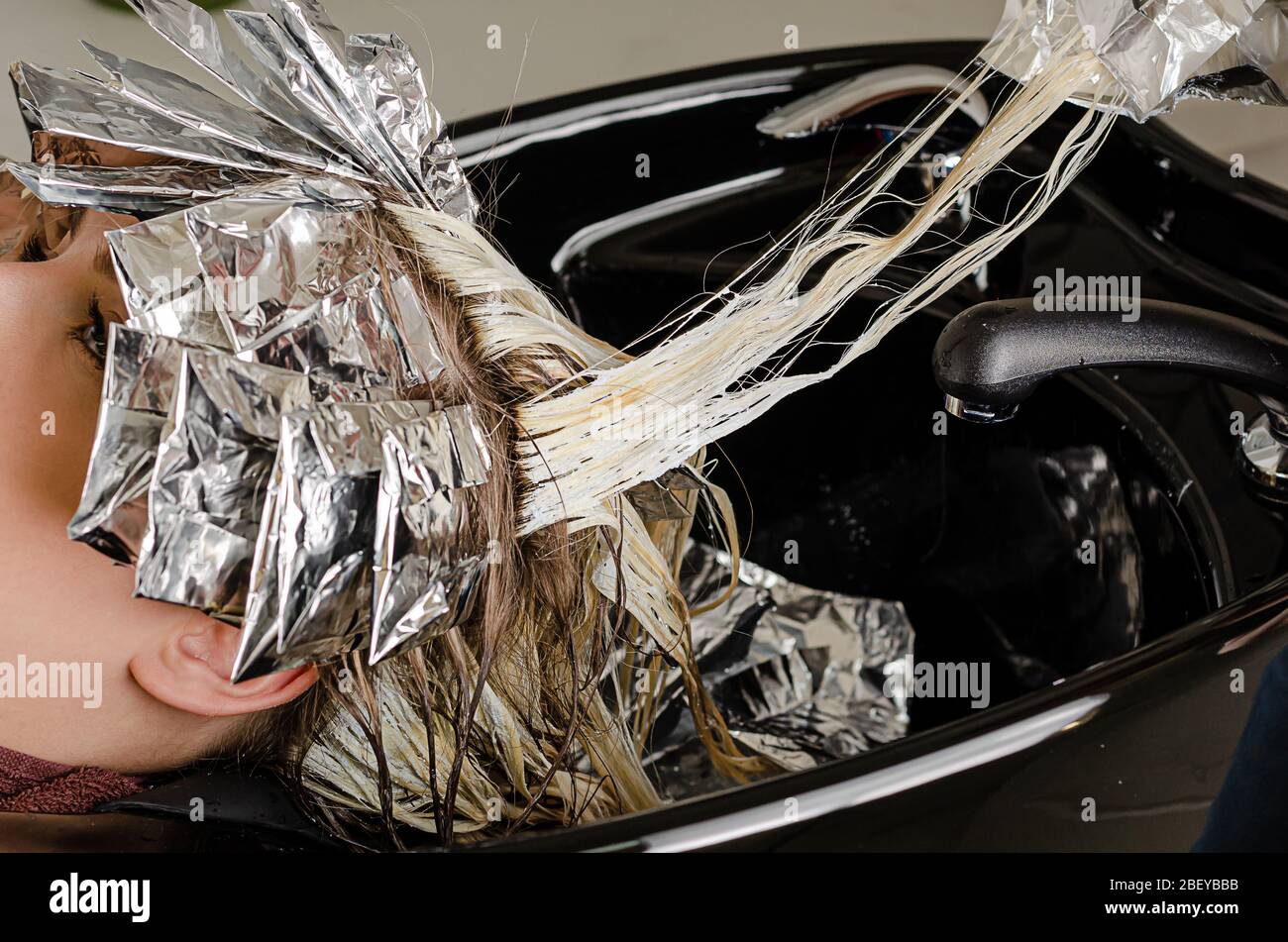 Set of hair dyeing process. Stylist is taking off the foil from models ...