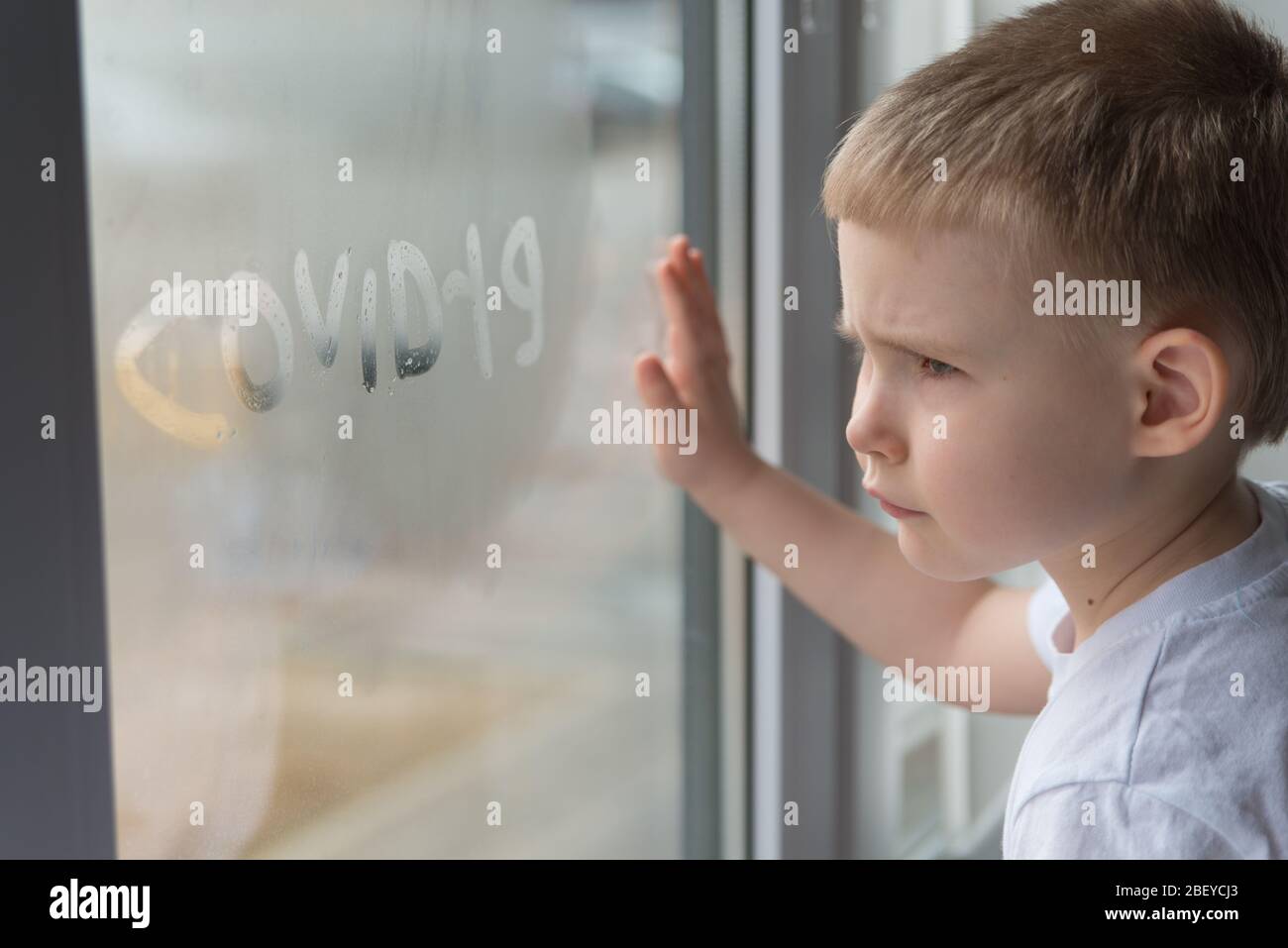 Sad 4 Years Old Boy Looking Through The Window and hold his hand on the ...
