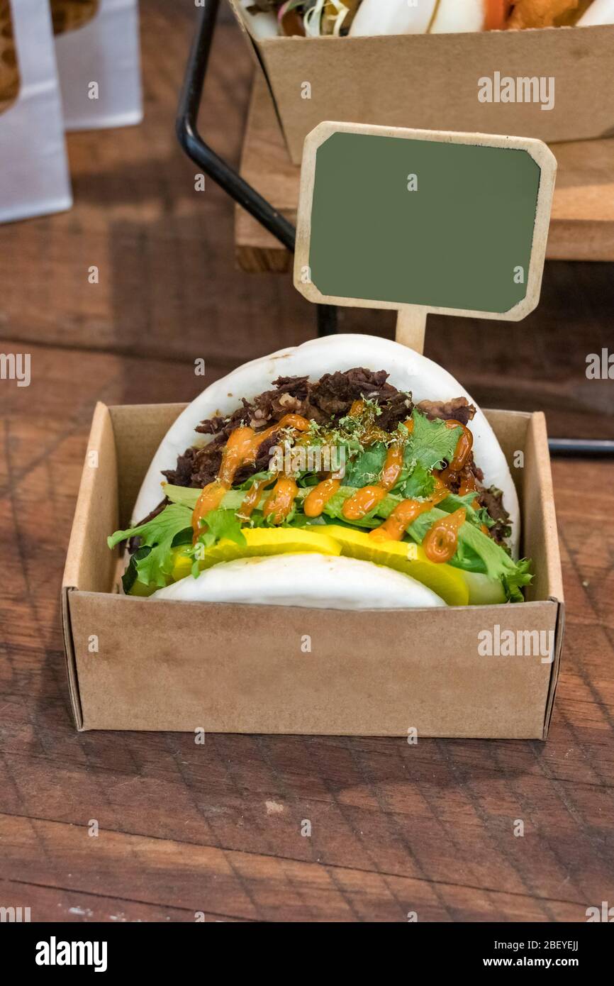 A Bulgogi asian beef burger bun placed on a cardboard box for sale a a ...