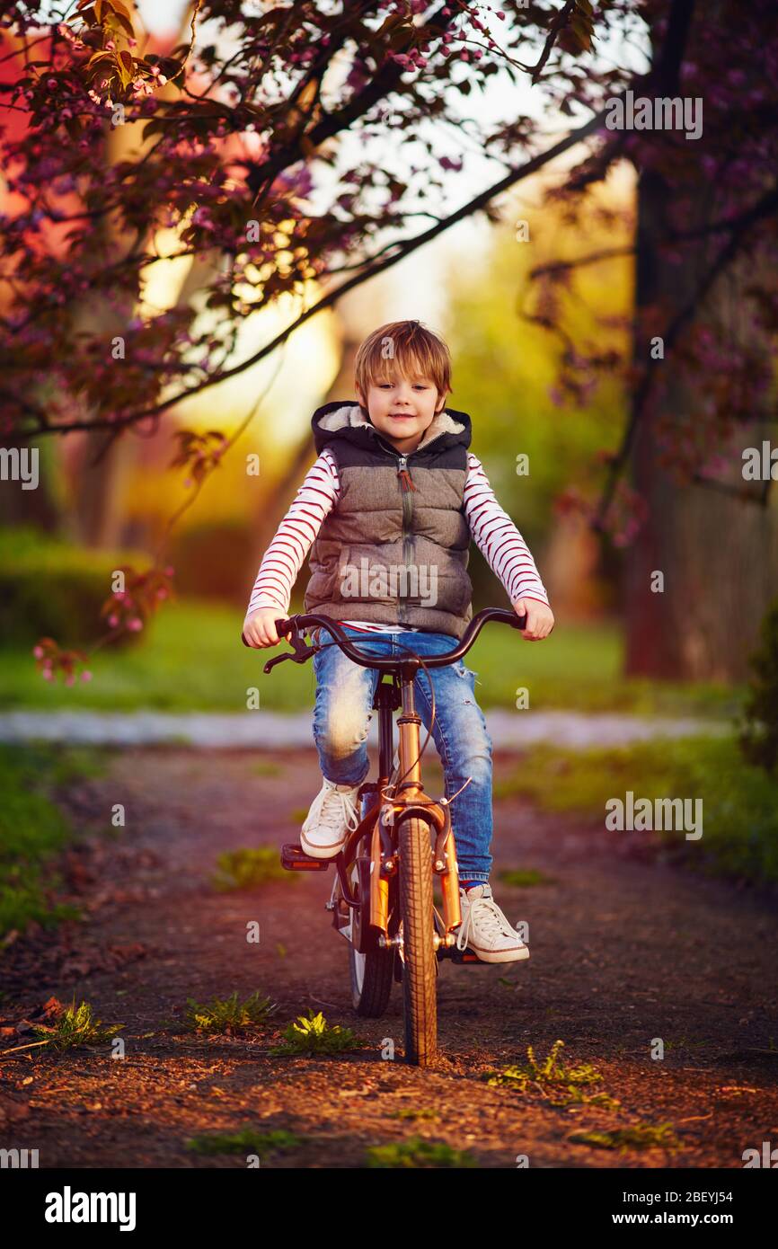 cute kid riding a bicycle through the spring park Stock Photo - Alamy