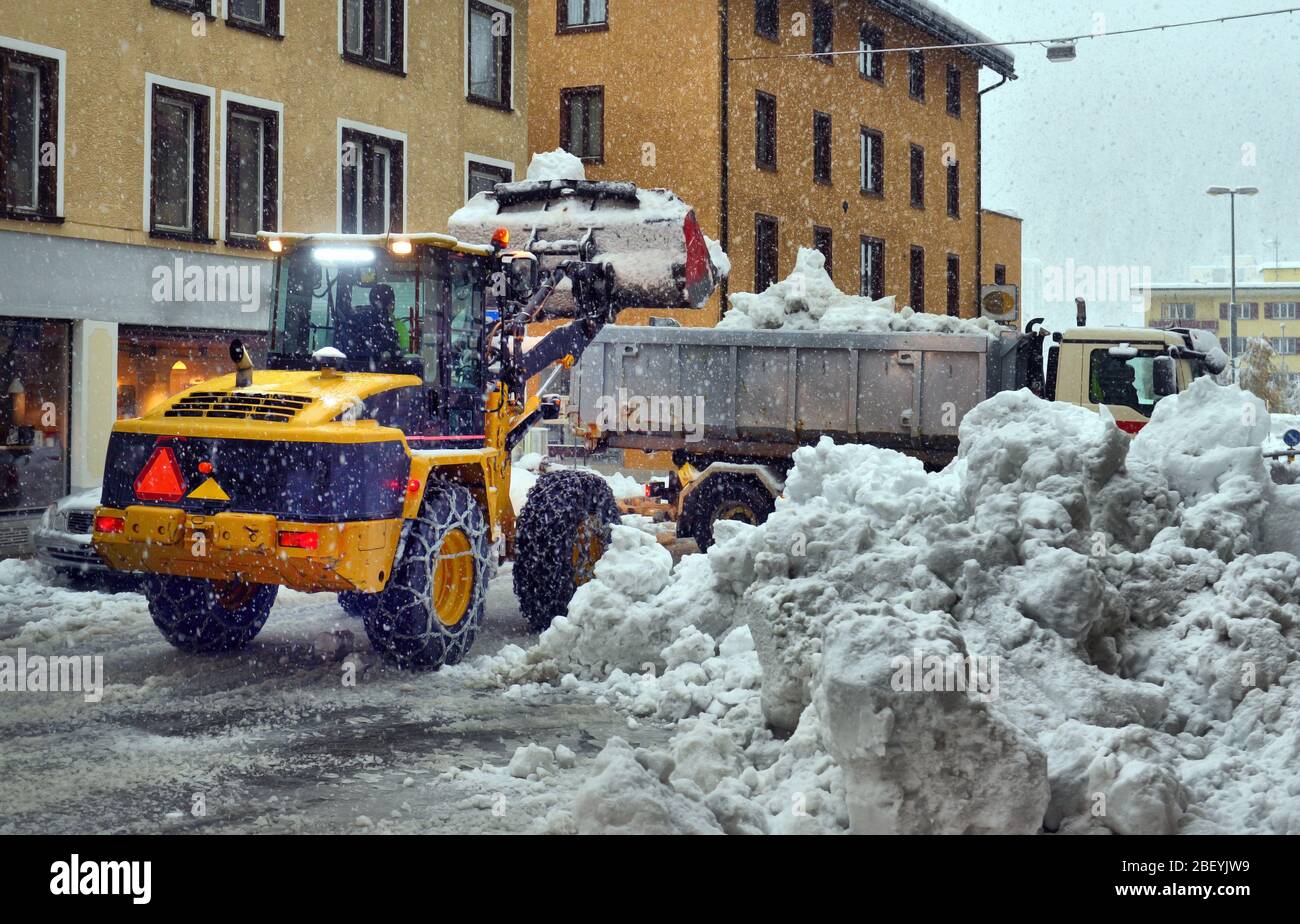 Snow cleaning tractor snow-removal machine loading pile of snow on a ...