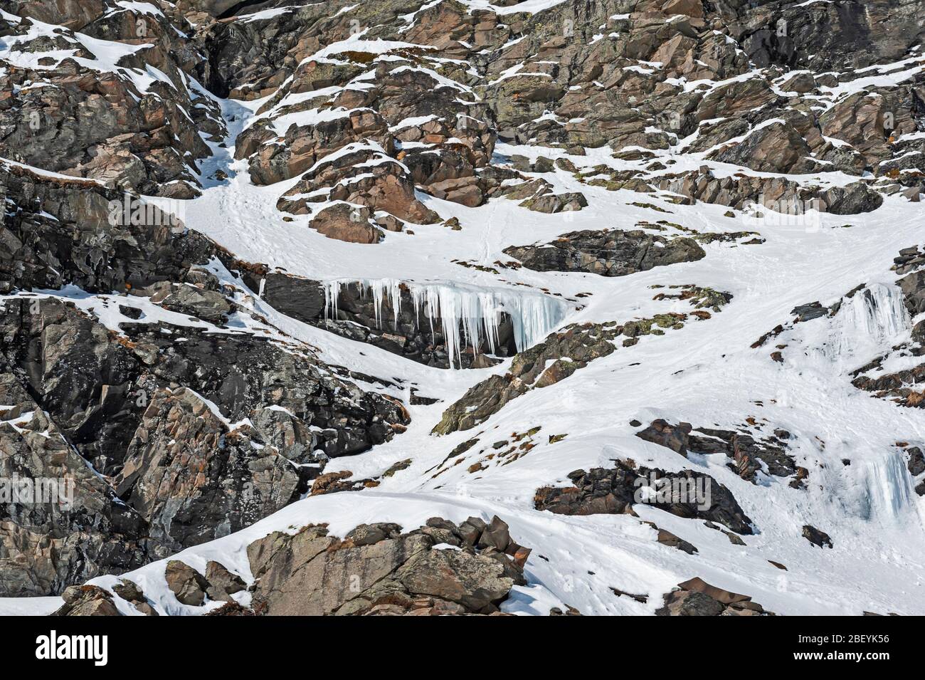 Rugged alpine rocky mountainside landscape with frozen waterfall ...