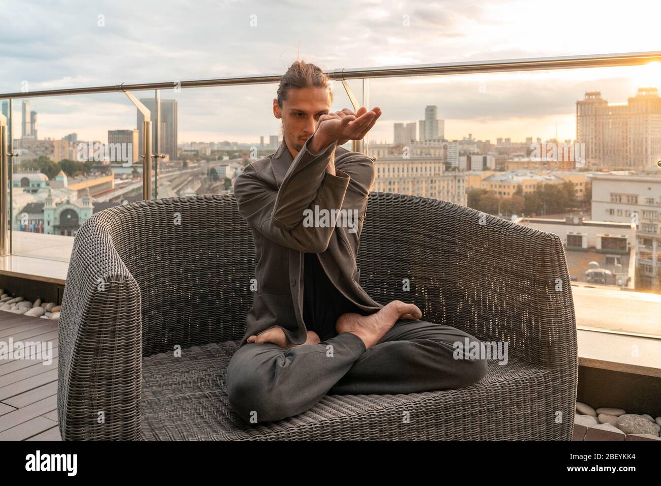 Young Man in Lotus Pose At Skyscraper Roof Relaxing From Stress At ...