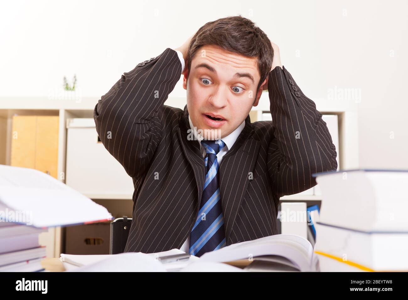 Businessman sits overwhelmed at a full desk Stock Photo - Alamy